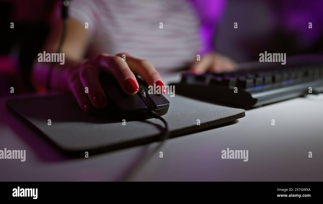 A woman with manicured nails uses a computer mouse and keyboard in a ...