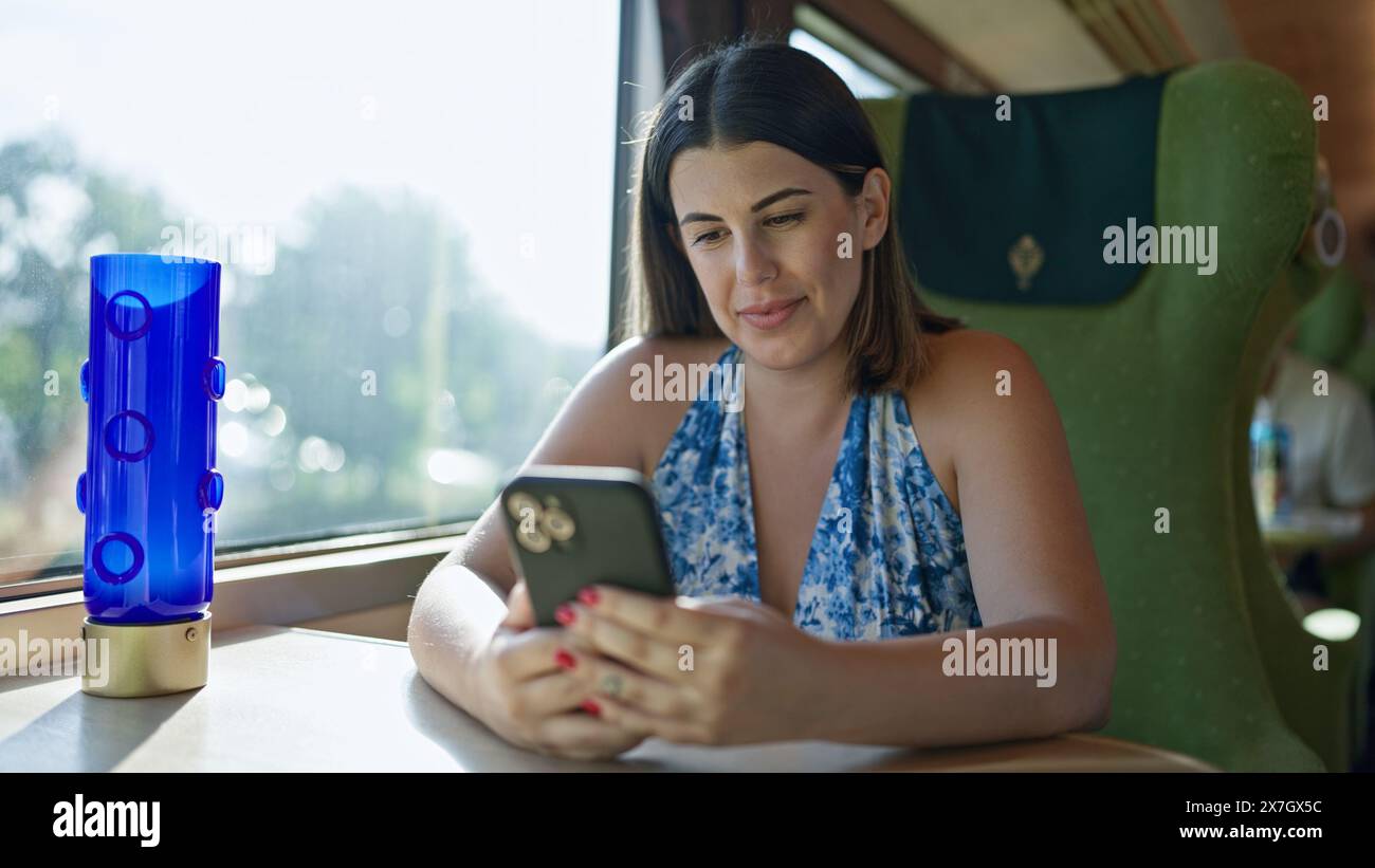Smiling beautiful hispanic woman sitting, happily texting on her ...