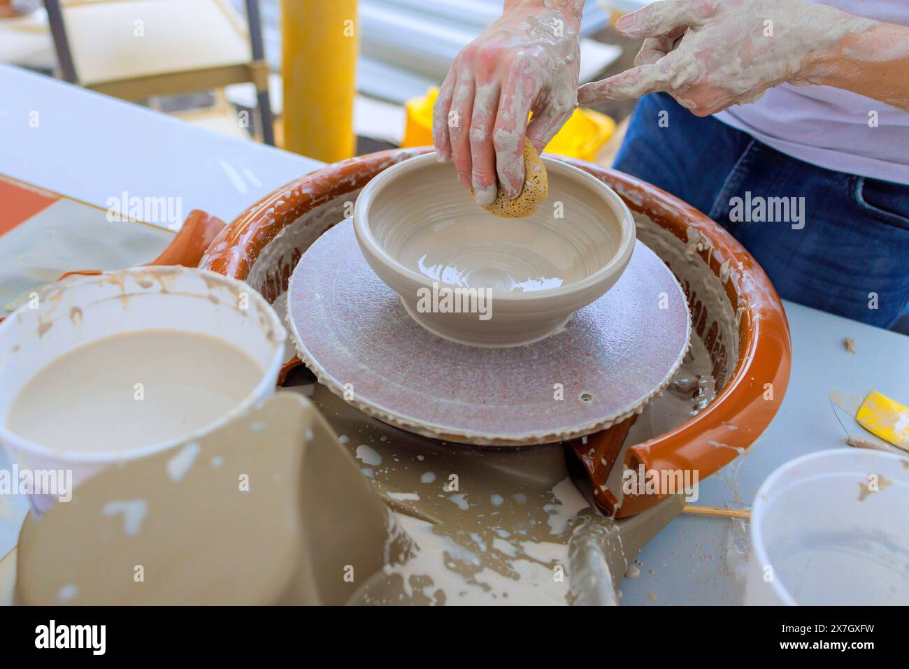 Using wet hands, ceramicist shapes soft clay on potter wheel Stock ...