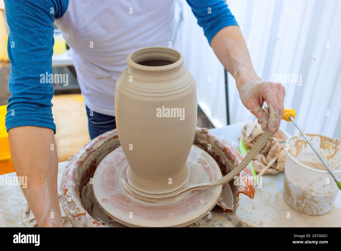 An potter hand sculpt shaping soft clay with wet hands on potter wheel ...