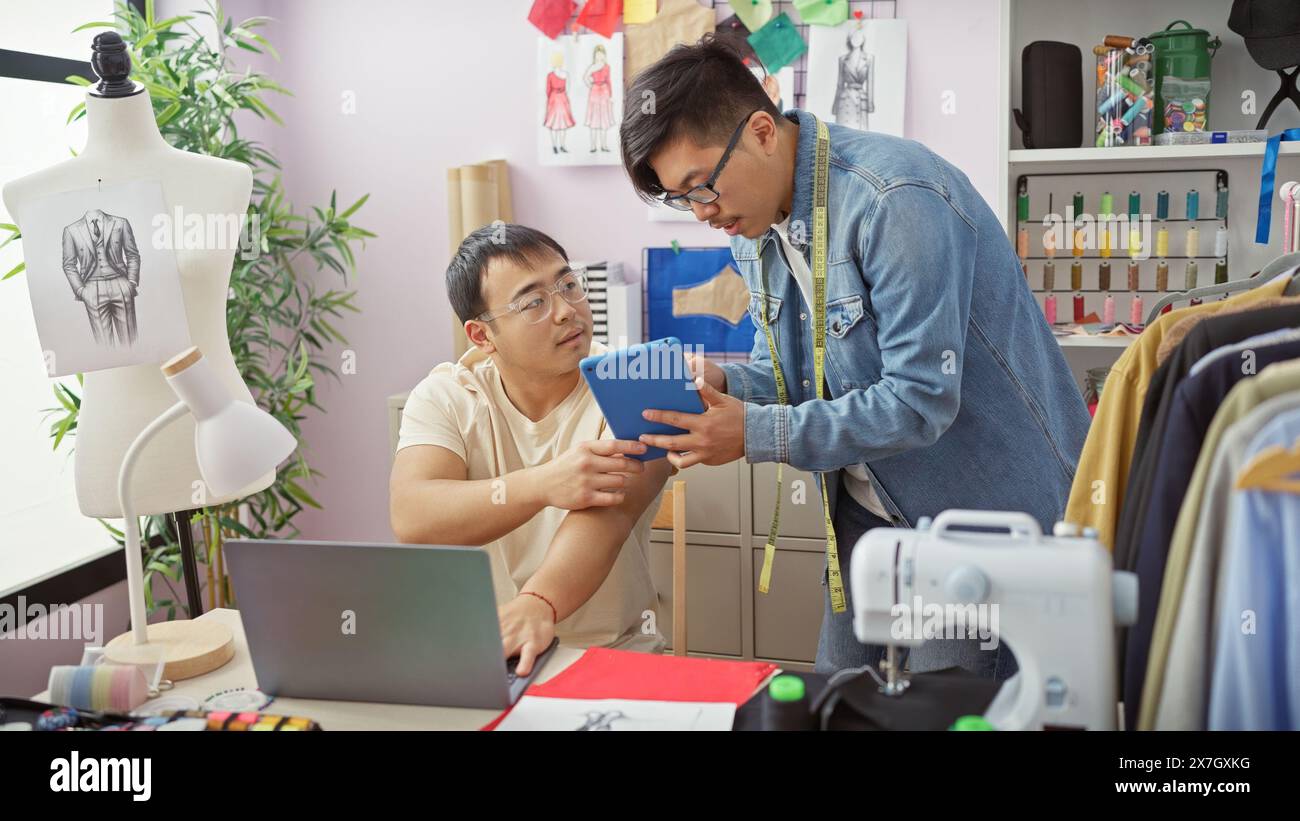 Two men collaboratively working in a creative tailor shop with a tablet ...