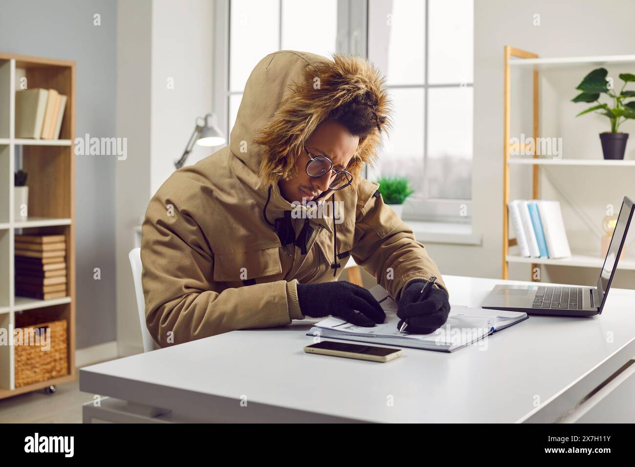 Young indian business man working in the cold at home on his laptop and ...