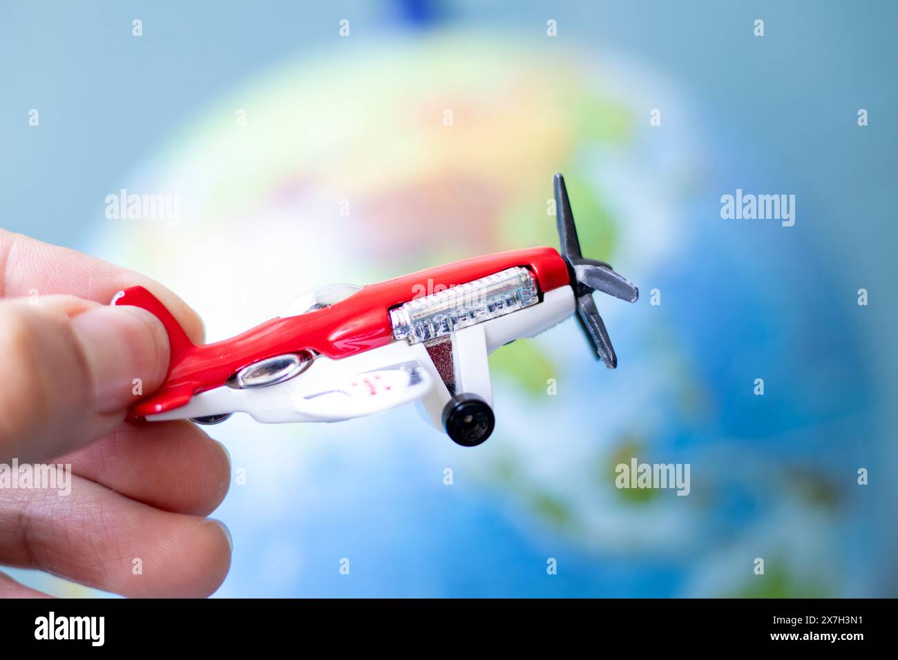 Man hand holding toy propeller plane in front of earth background ...