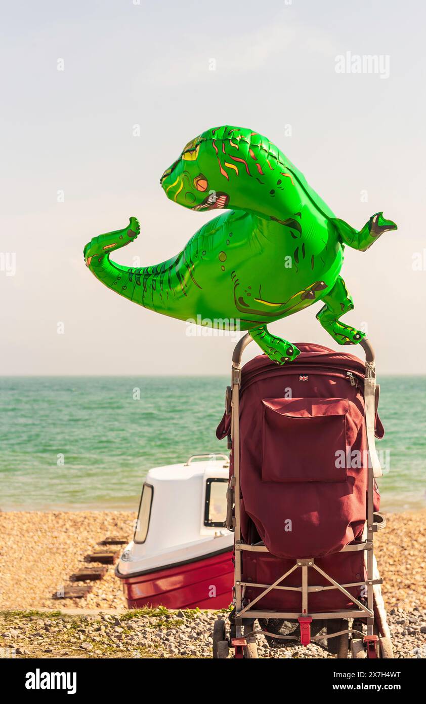 Pram with dinosaur ballon looks out over the beach at Bexhill on sea ...