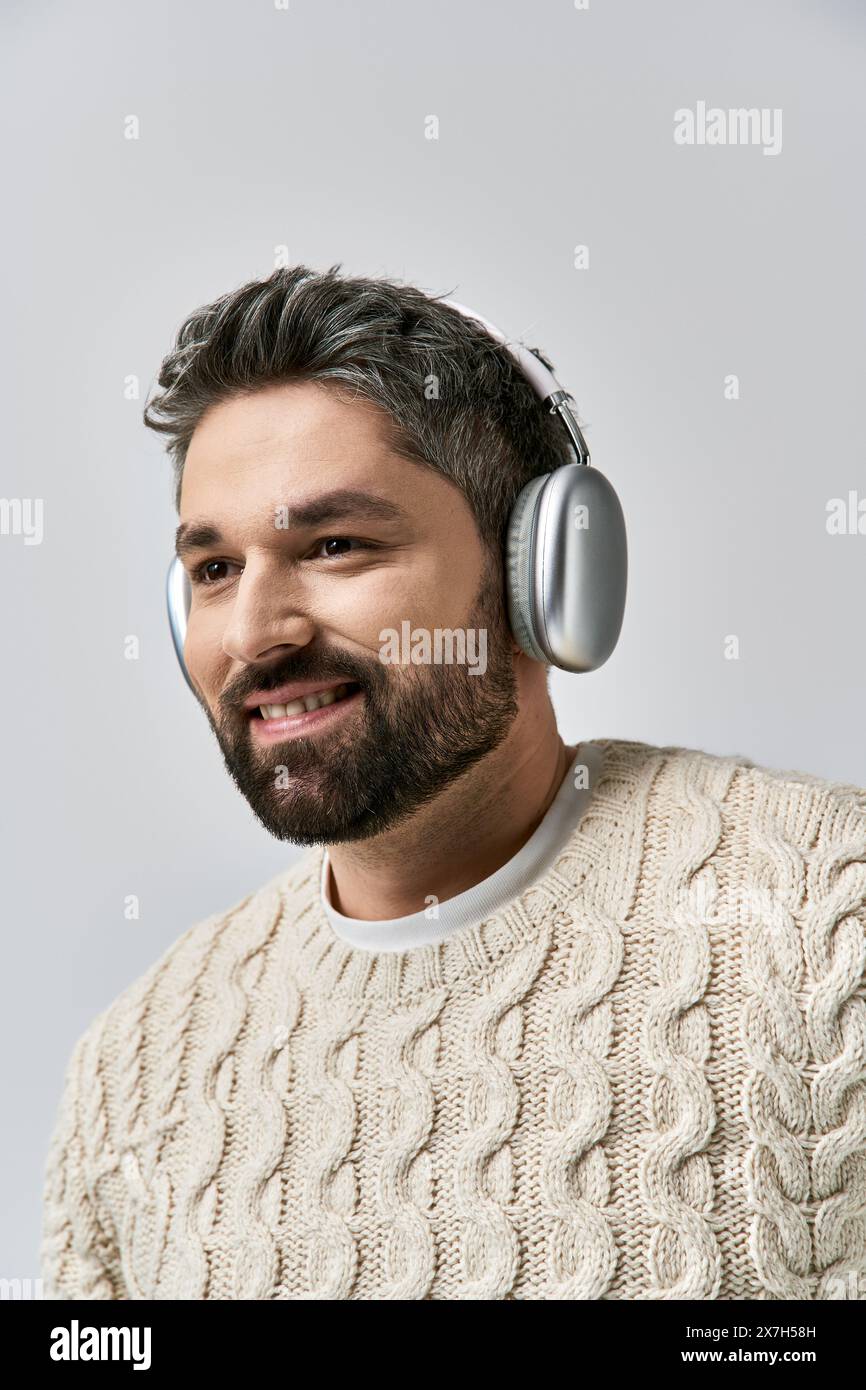 A captivating man with a beard wearing headphones and a white sweater ...