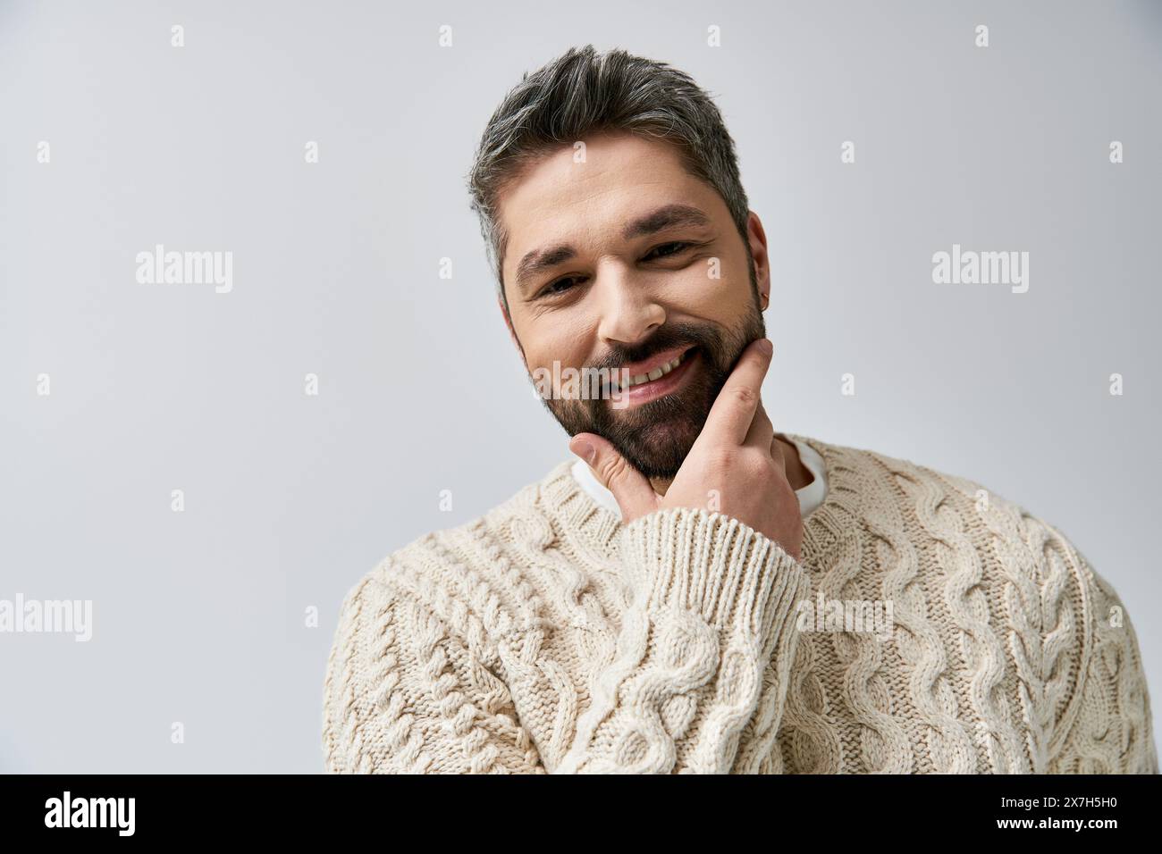 A captivating man with a beard striking a pose in a white sweater ...