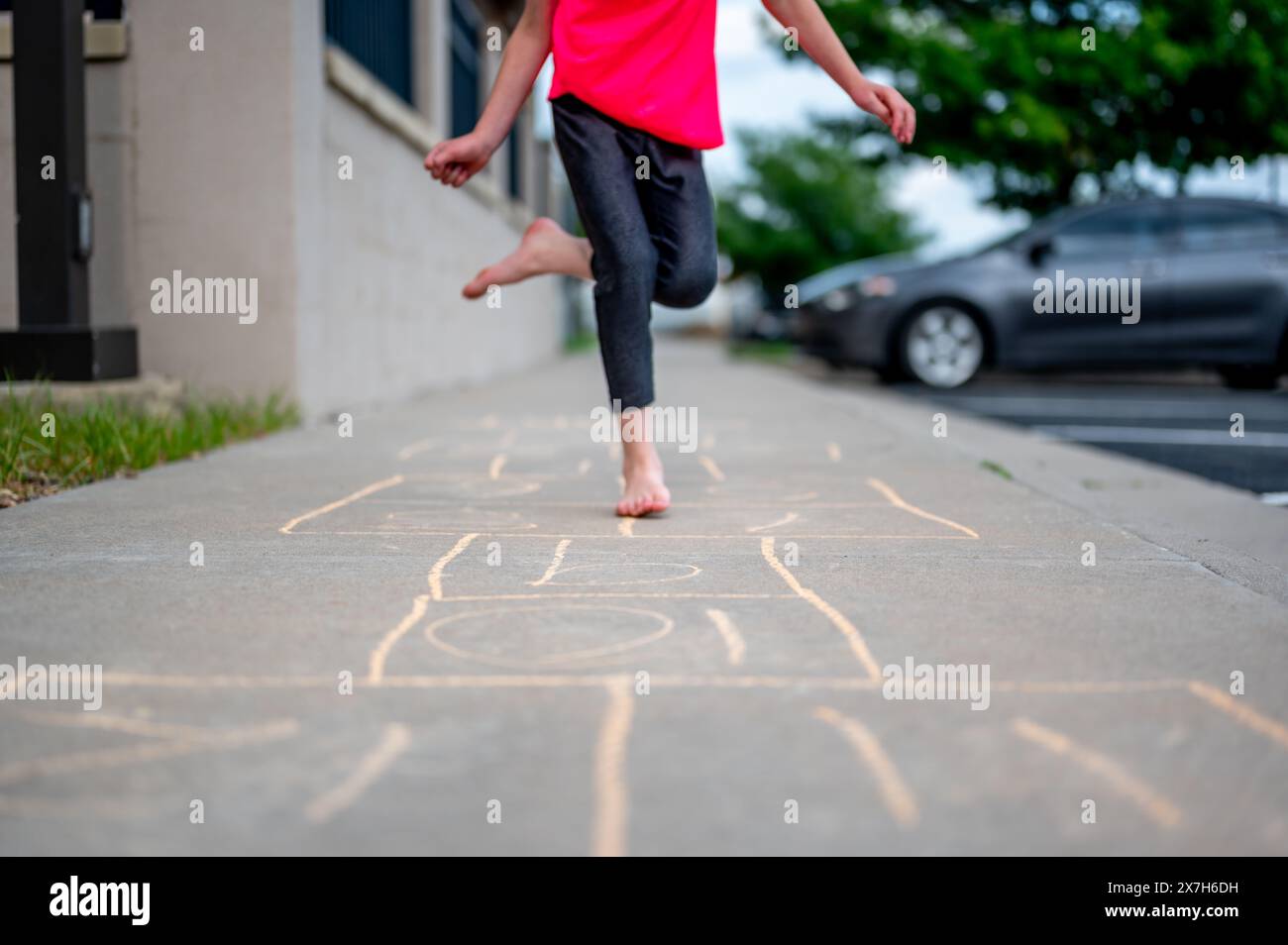 Selective focus on chalk numbers with a girl playing hop-scotch ...