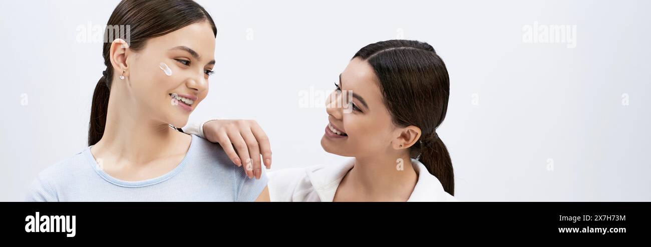 Two pretty, brunette teenage girls, best friends, standing together ...