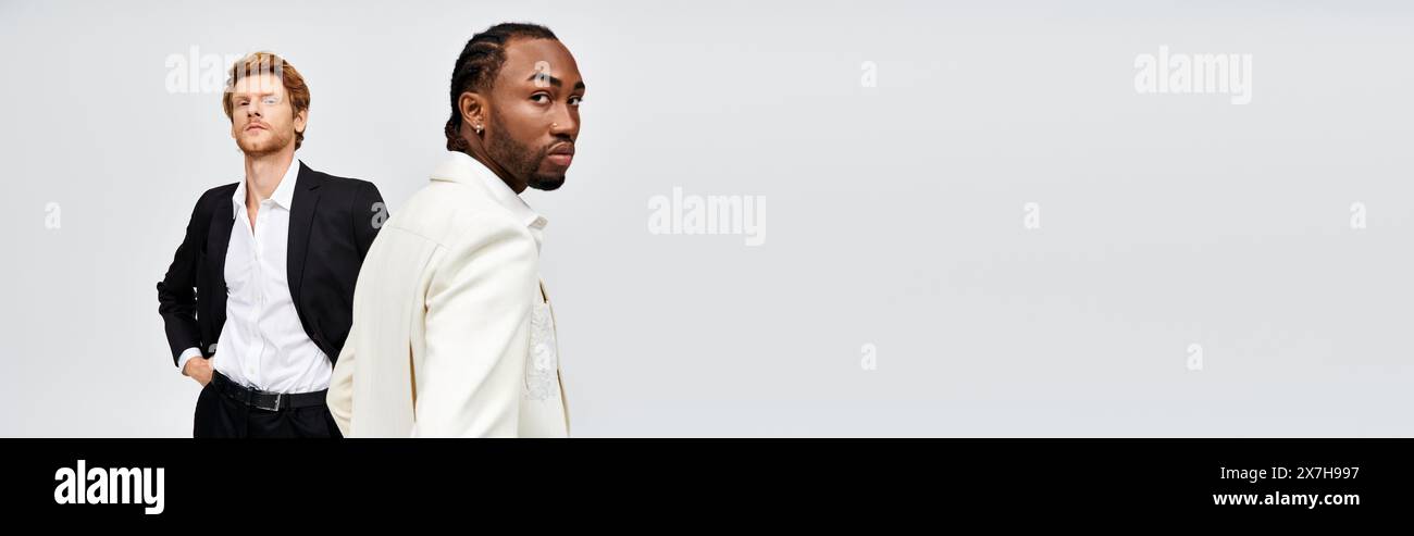 Two elegant multicultural men stand side by side against a white ...