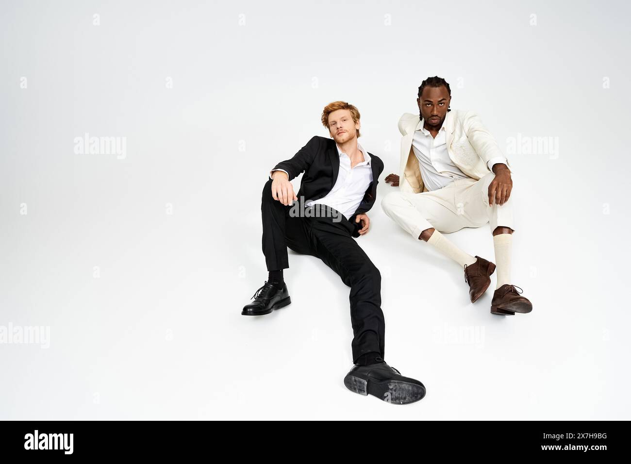 Two multicultural men with elegant style sitting side by side Stock ...