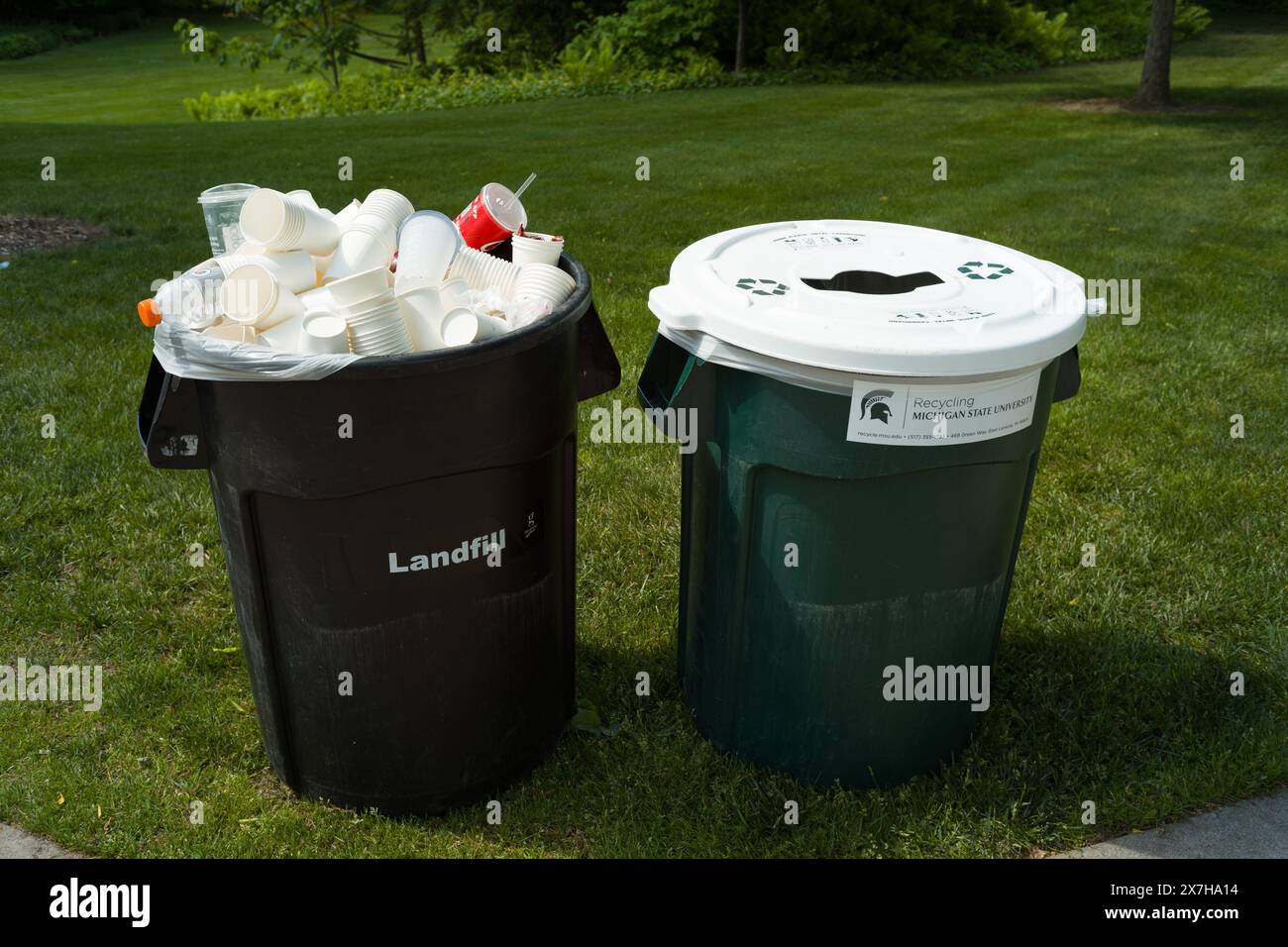 A recycle bin and overflowing landfill trash bin on the campus of ...