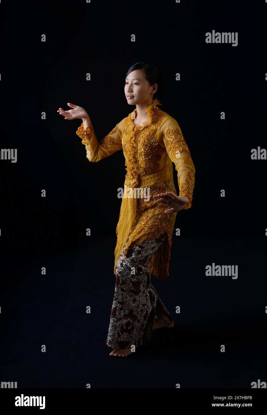 Indonesian woman performing a traditional dance in ornate, golden ...