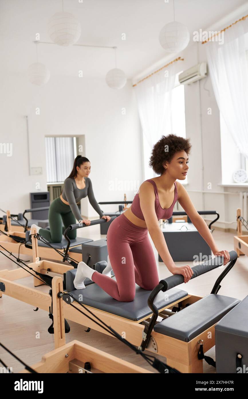 Young women in gym, exercising on stationary machine with focused ...