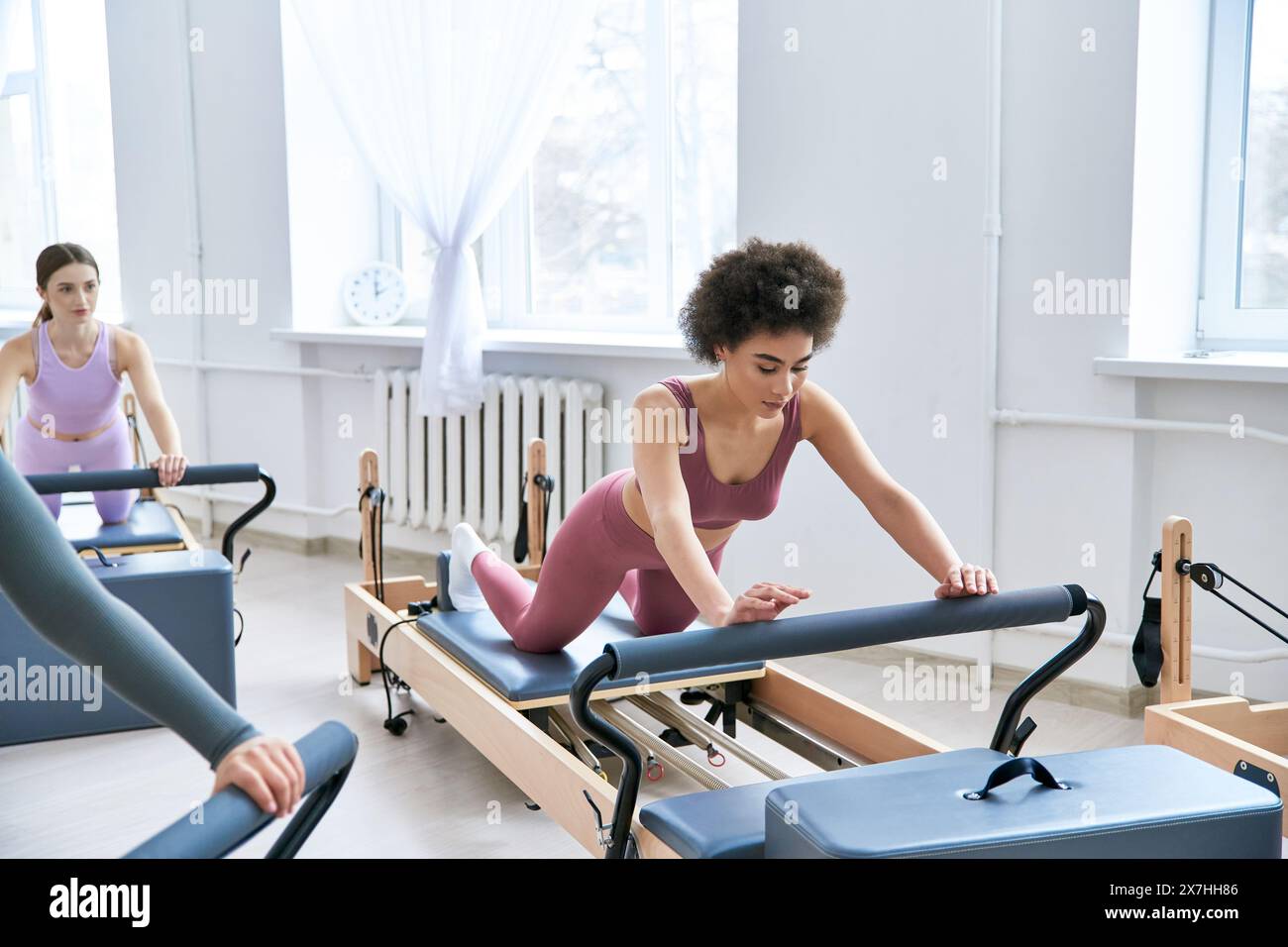 Women of diverse backgrounds performing Pilates exercises in a group ...
