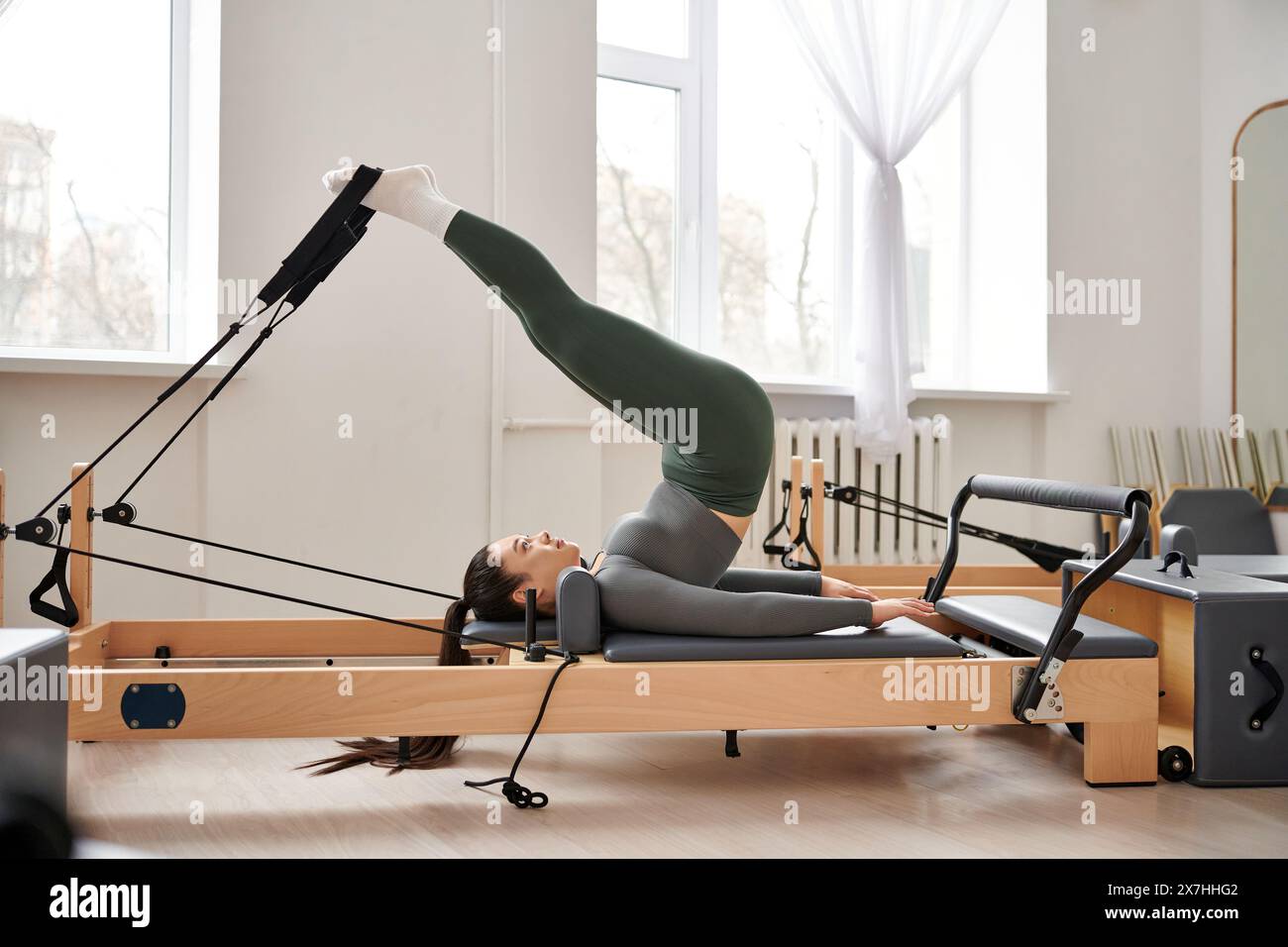 Appealing woman gracefully performs exercises during a pilates lesson ...