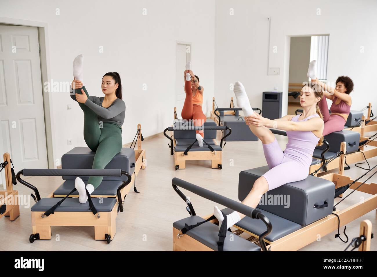 Active women engaged in a Pilates class, focused on stretching and ...