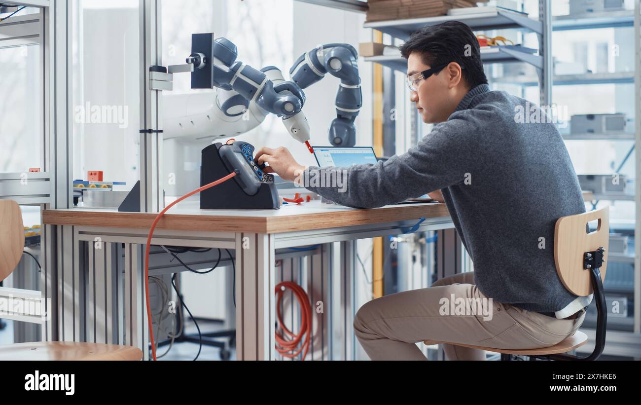 Asian Engineer Moving Robotic Arm with Control Panel And Developing ...