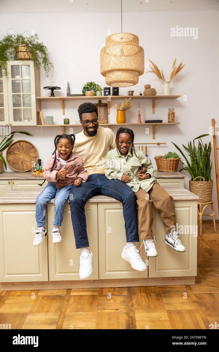 Cheerful dad with happy little children daughters having fun at home ...