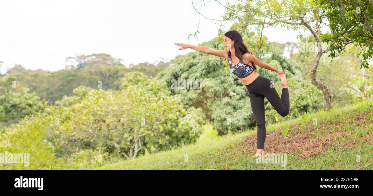 lifestyle: young latina practices Tuladandasana posture in nature Stock ...