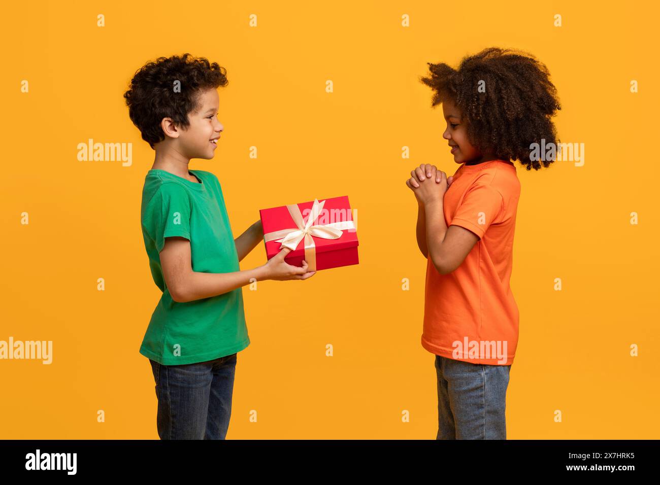 Two Children Exchanging Presents on Yellow Background Stock Photo - Alamy