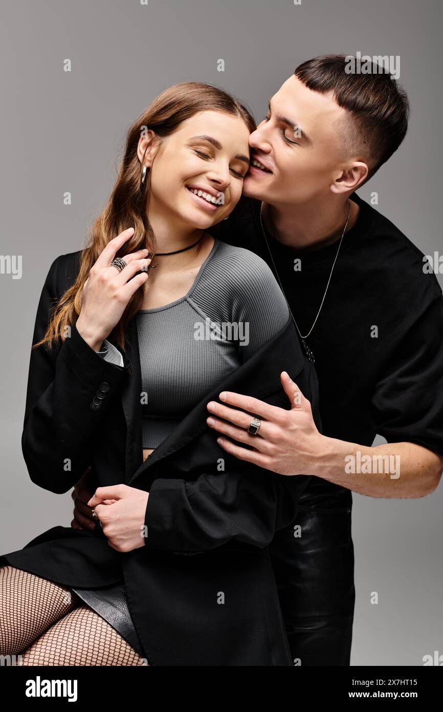 A young couple in love poses in a studio with a grey background ...