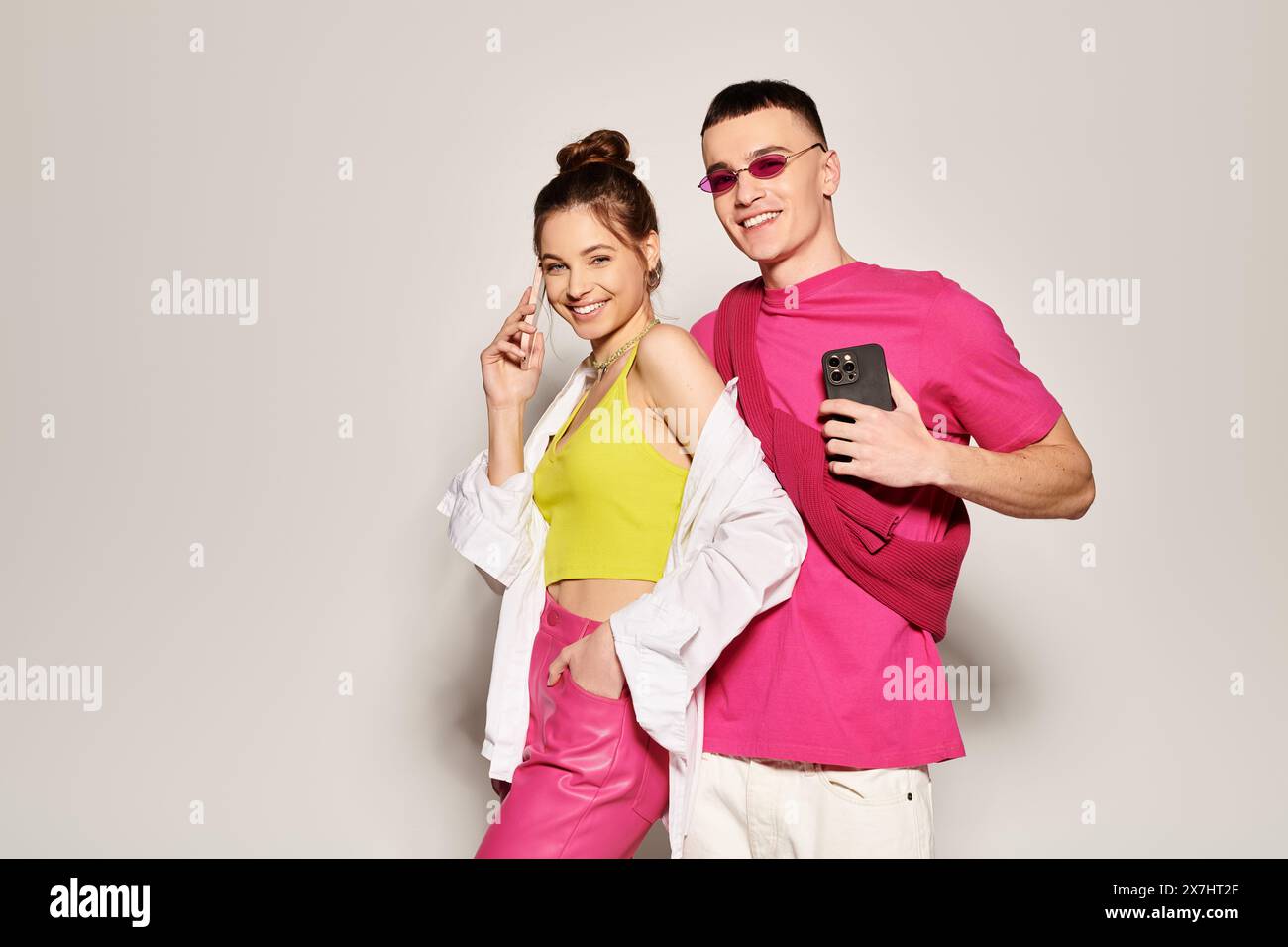 A stylish young couple in love posing together in a studio with a grey ...