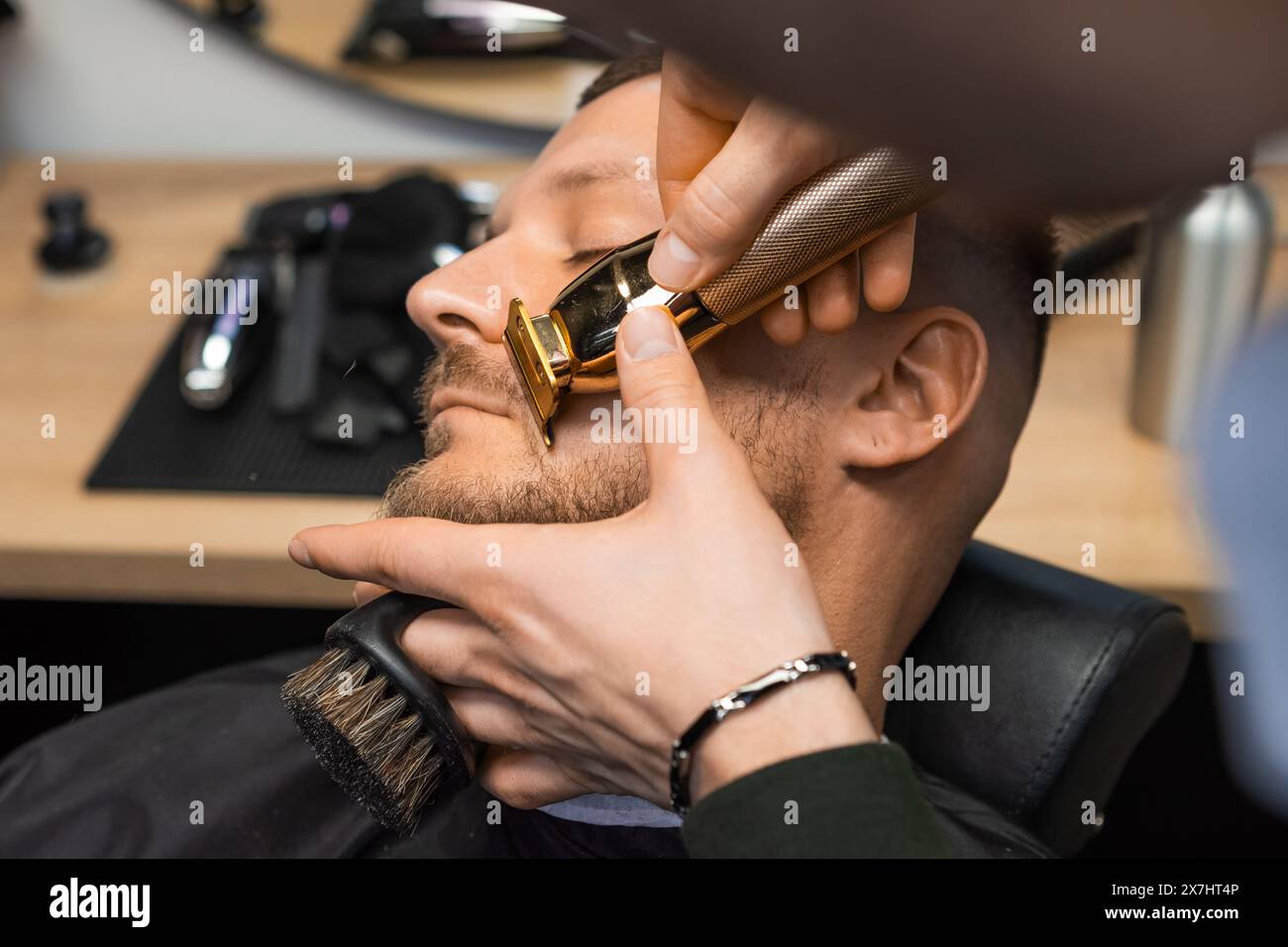 Barber maneuvers the trimmer along the clients cheek, carefully cutting ...