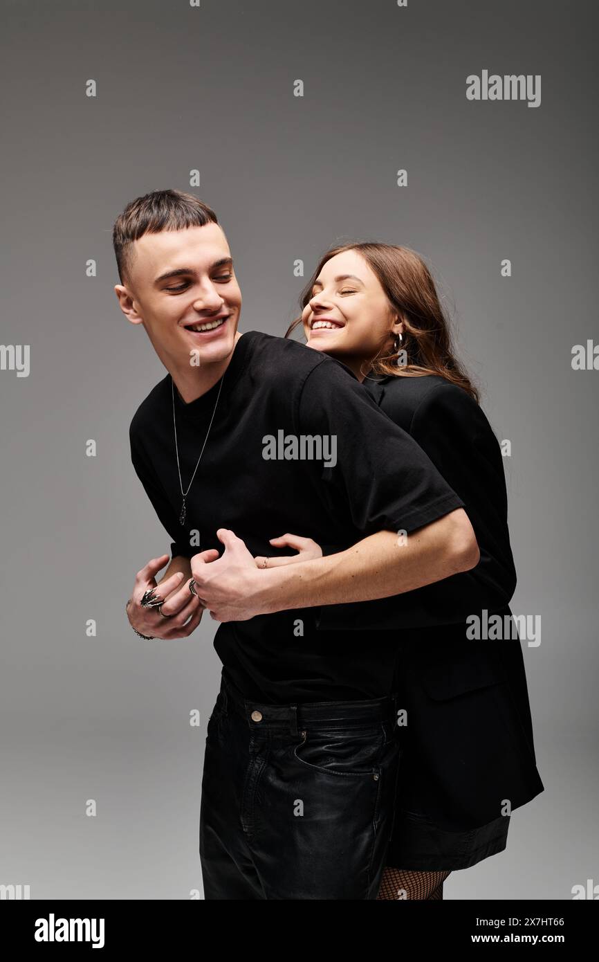 A young couple tenderly embraces each other against a neutral grey ...