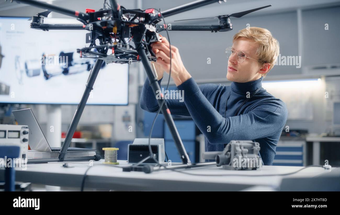 Young Caucasian Male Engineer Installs Processor in the Drone and Types on Laptop. Designing ...