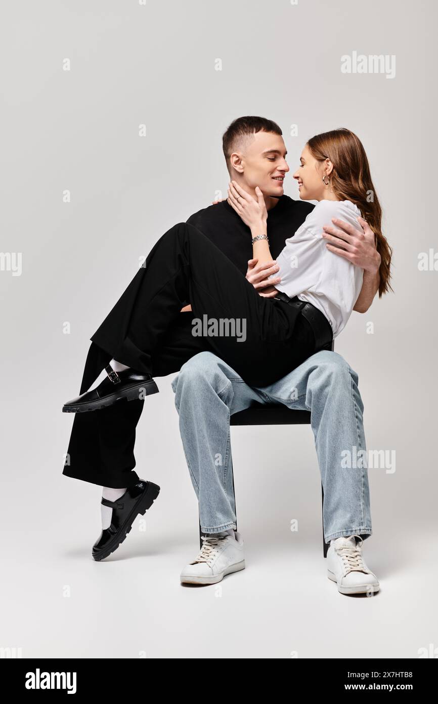 A young couple seated on a chair, sharing an intimate moment ...
