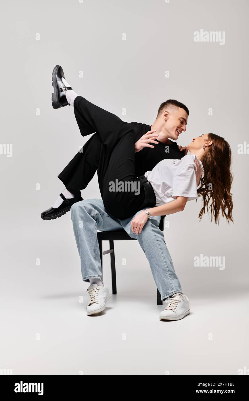 A young couple sits comfortably on a chair, their bodies close, exuding ...