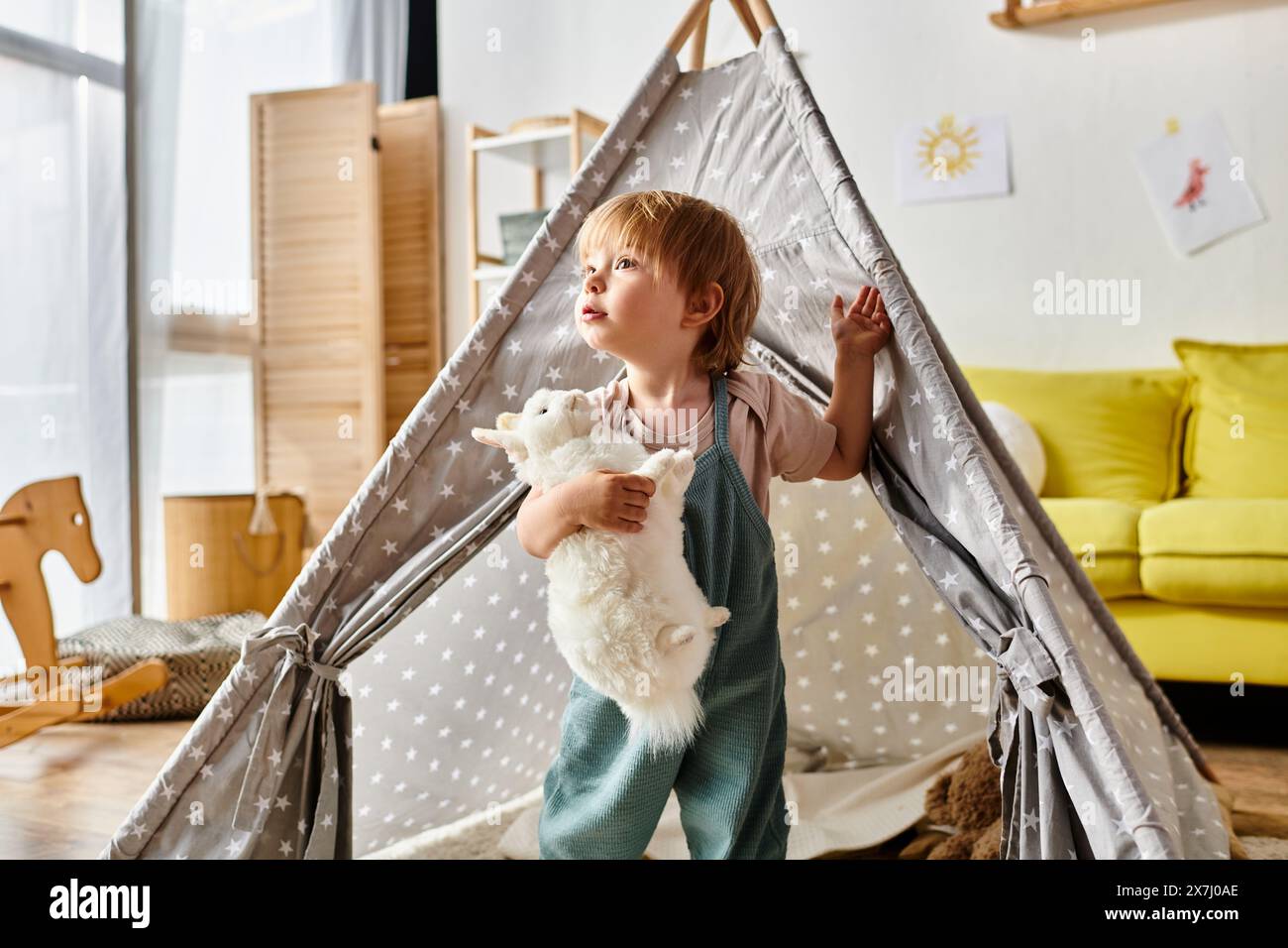 Toddler girl cuddling a stuffed animal inside a teepee, creating a ...