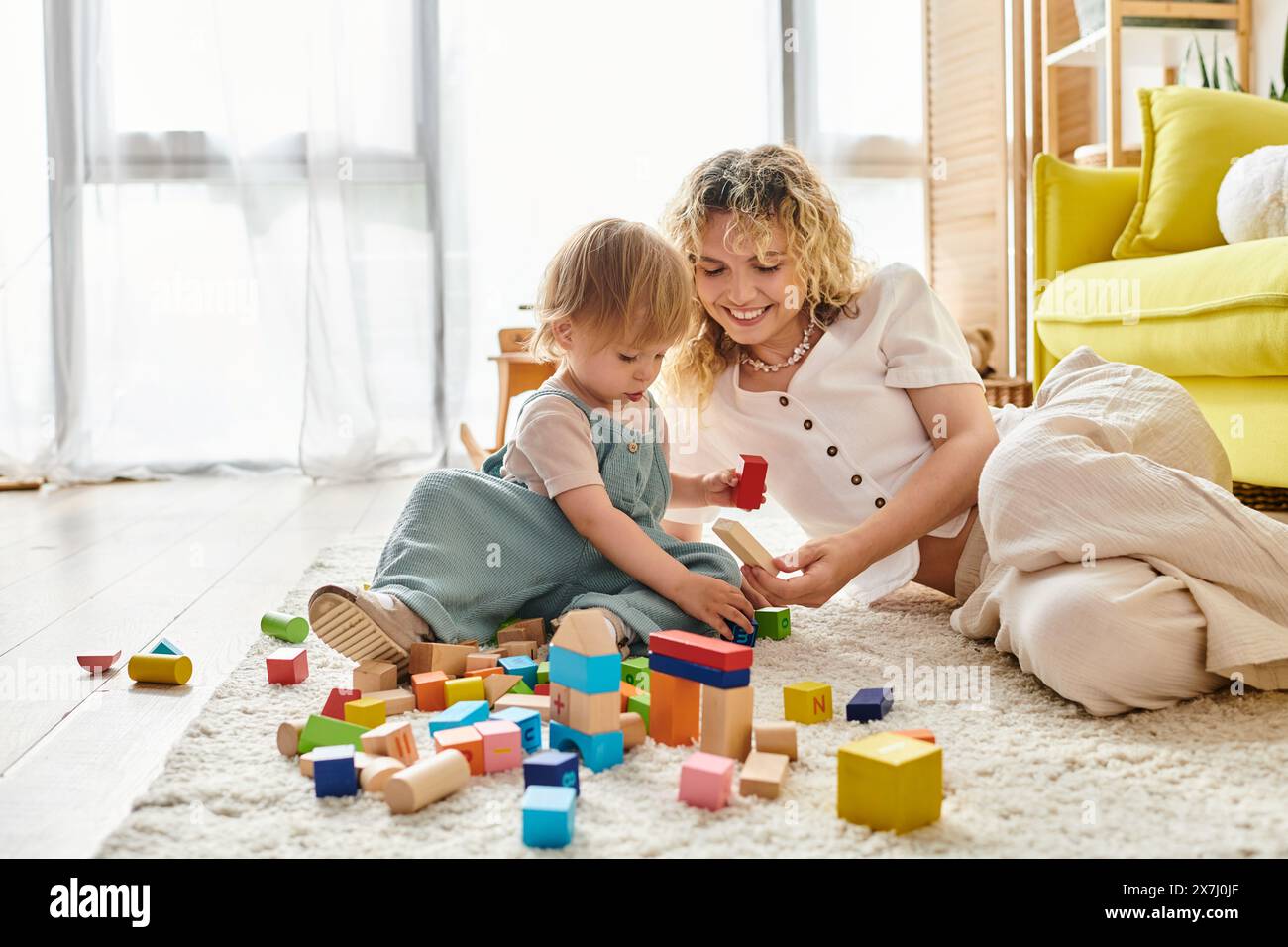 A curly mother and toddler daughter enjoy a playful moment on the floor, building structures ...