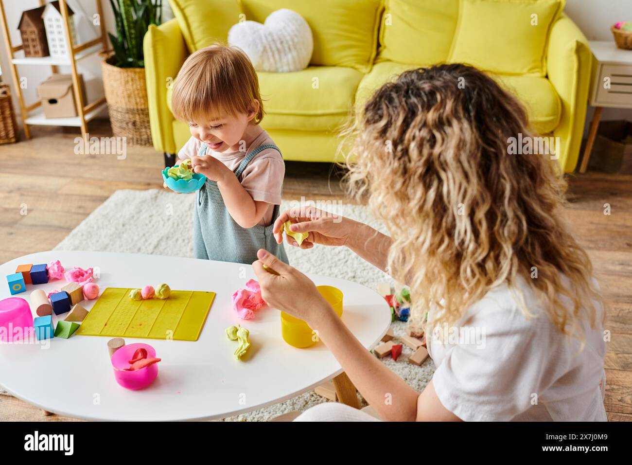 A woman with curly hair and her toddler daughter deeply engaged in ...