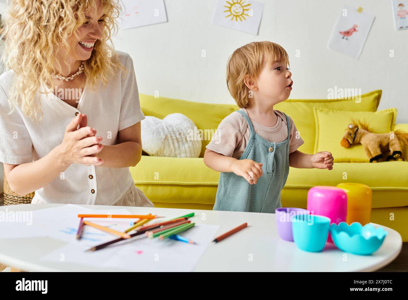 A curly mother and her toddler daughter joyfully engage in colorful ...