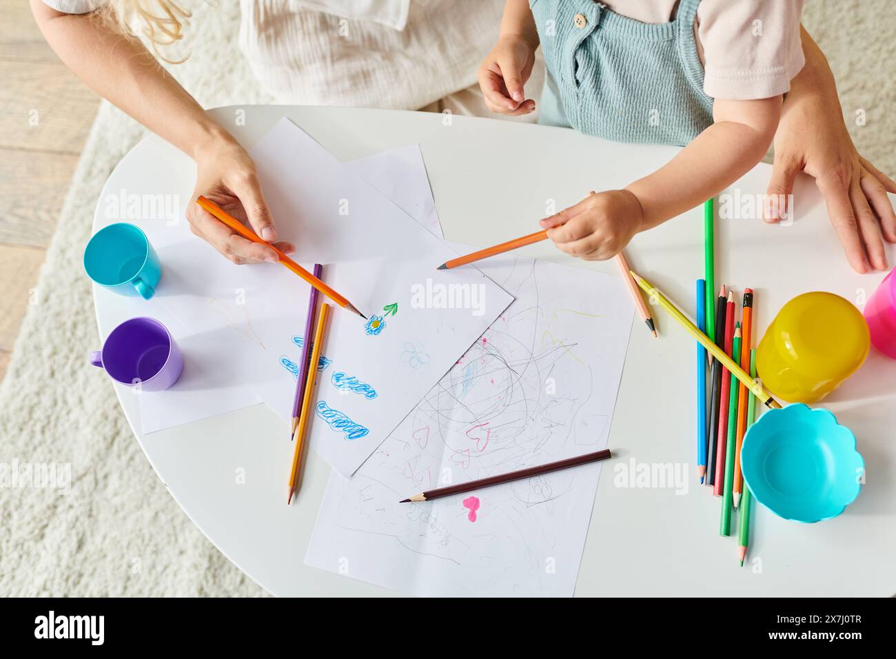 toddler and mom sit at a table drawing with colorful pencils and ...