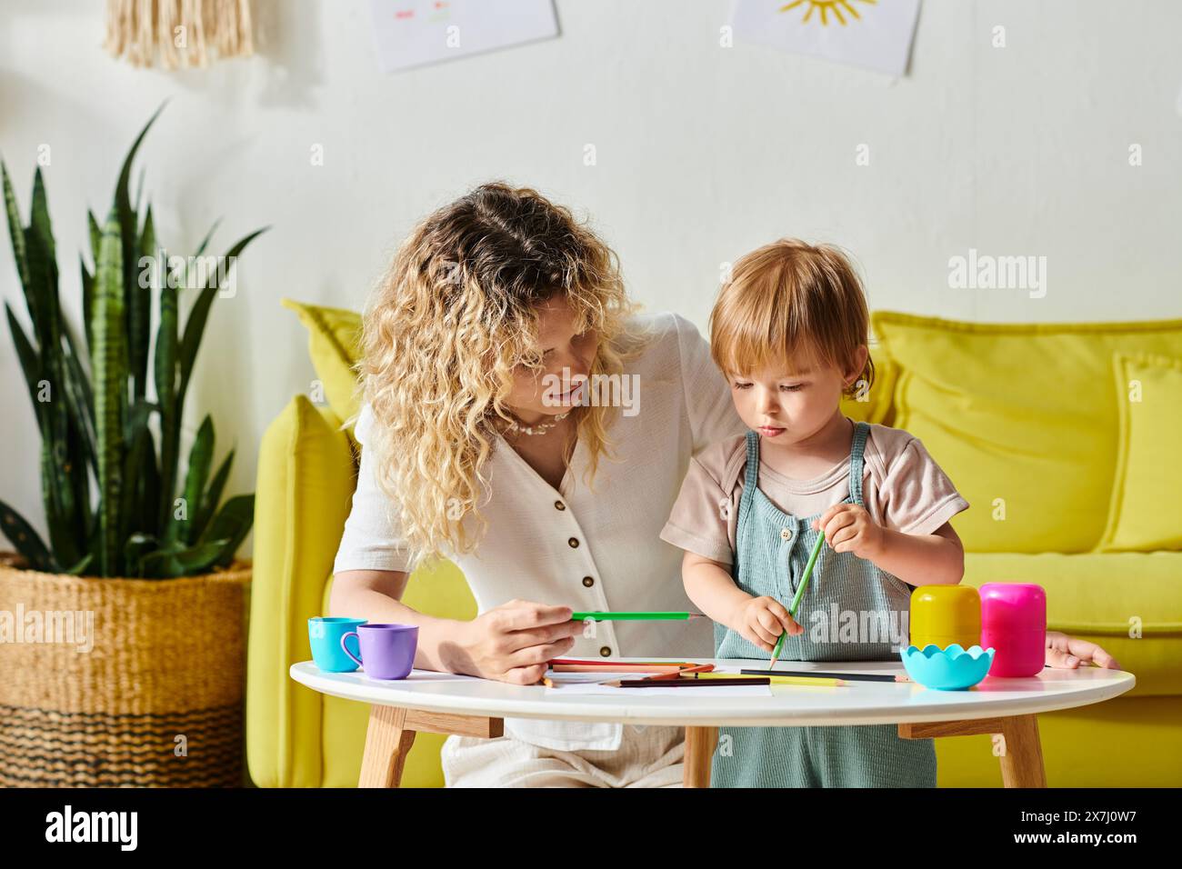 A curly-haired mother and her toddler daughter happily engage in ...