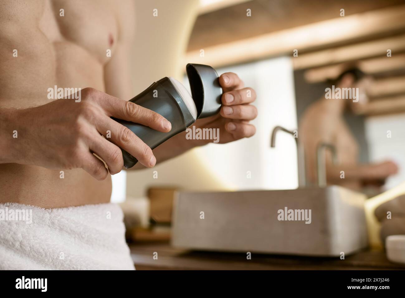 A handsome man in a towel using deodorant after his morning routine ...