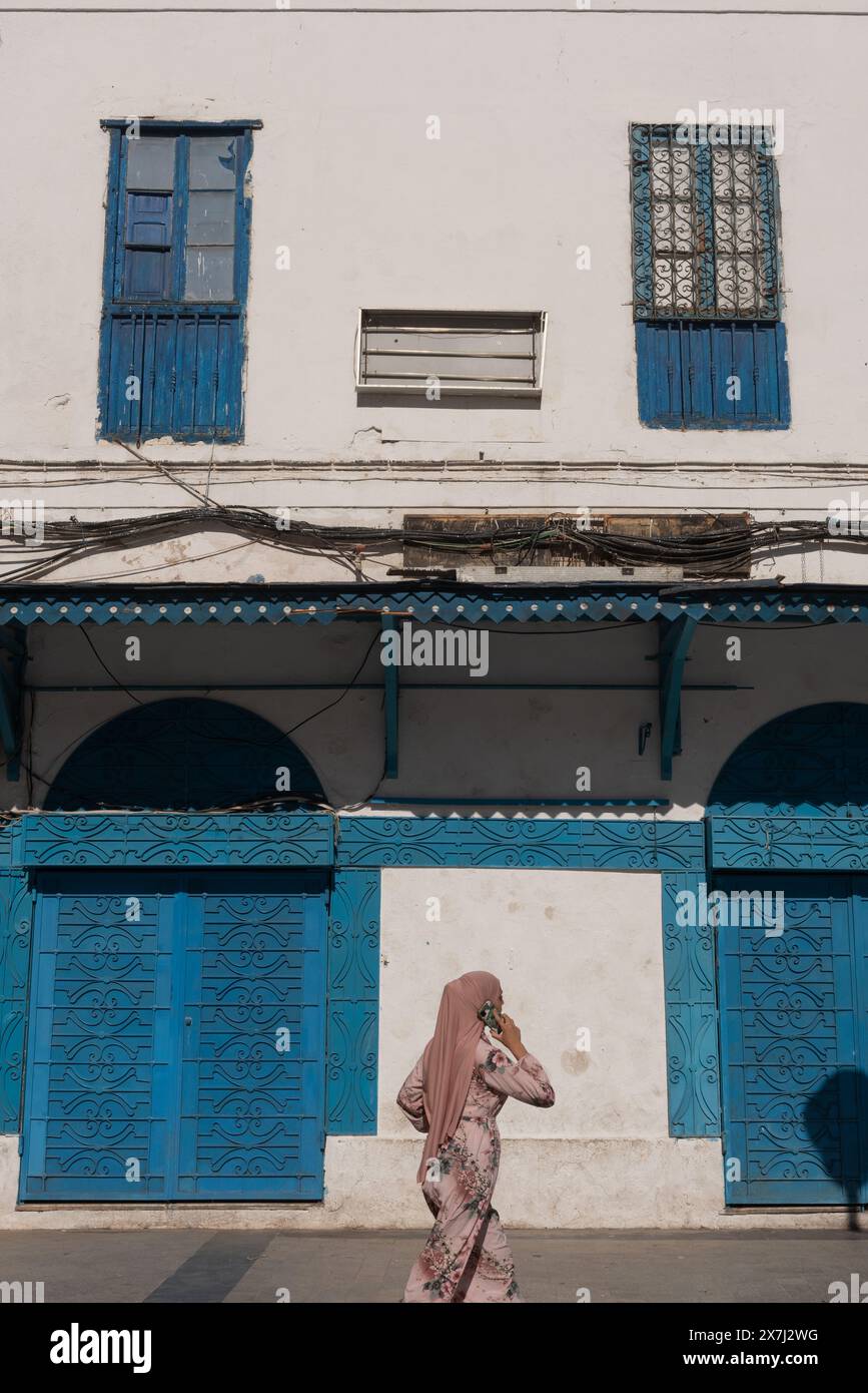 Tunis, Tunisia. 4th May 2024 A Muslim using a cell phone walks past ...