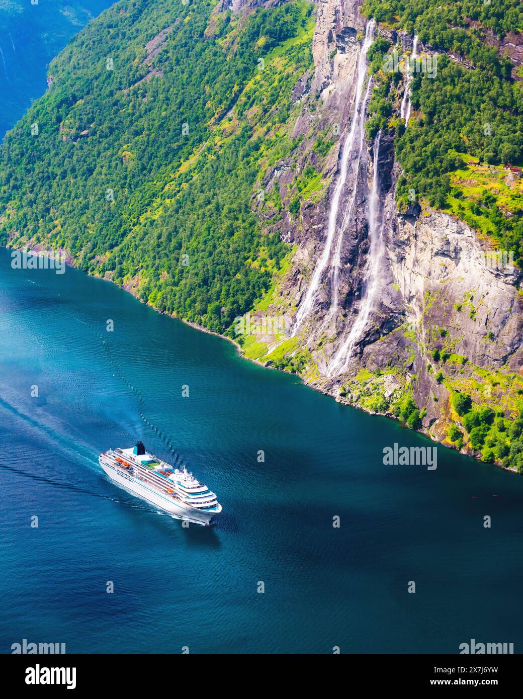 A big cruise liner floats by famous Seven Sisters waterfalls in clear ...