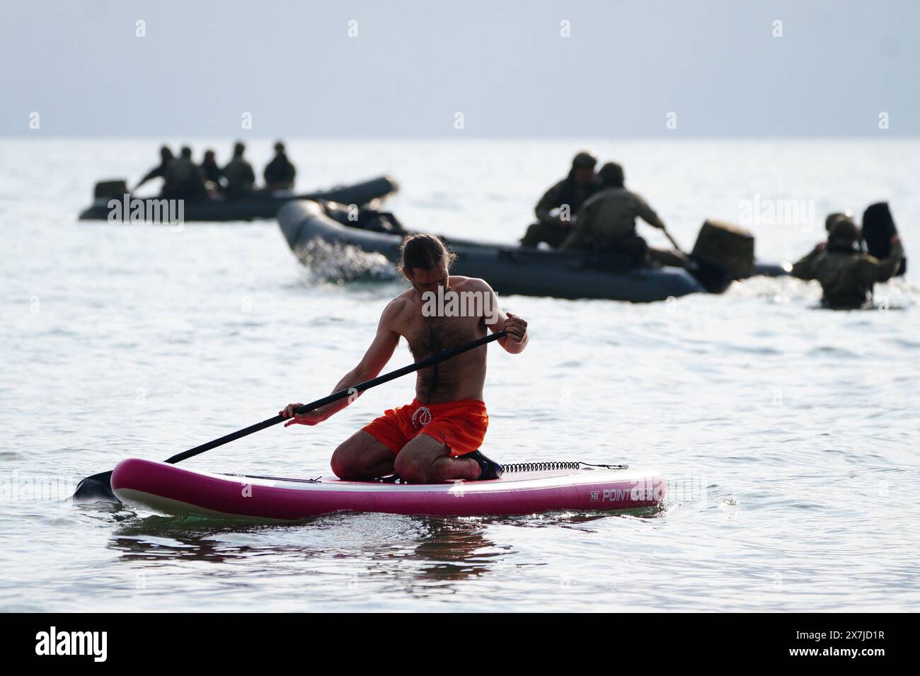 A puddle boarder passes members of Armed Forces personnel from 47 ...
