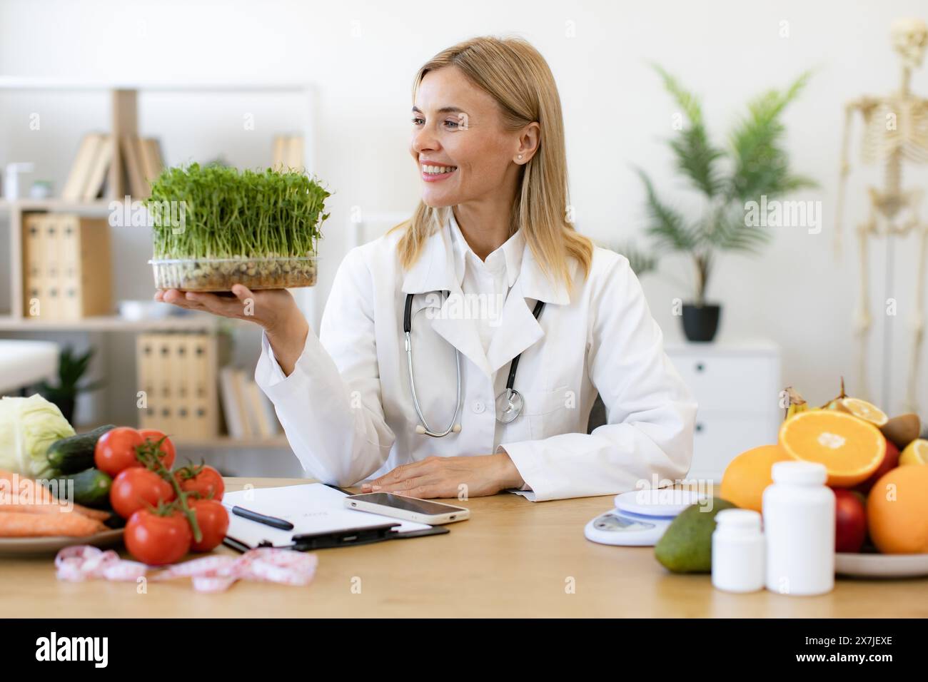 Charming Caucasian woman in doctor's coat with microgreens Stock Photo ...