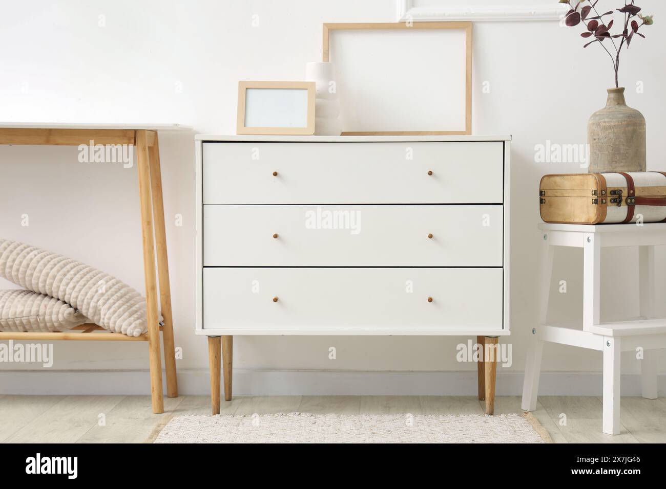 Cabinet with frames, ladder and table near white wall Stock Photo - Alamy