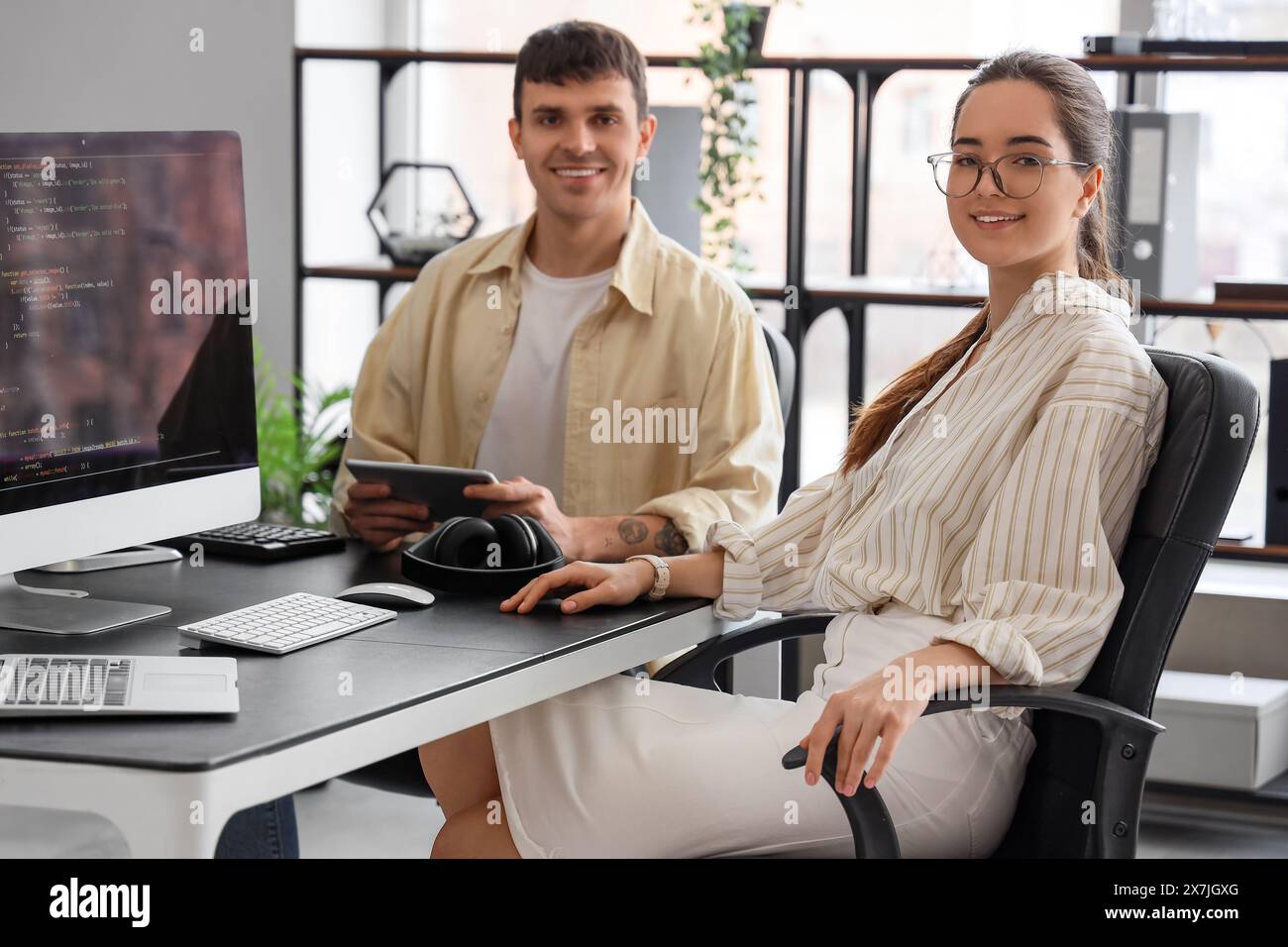 Male programmer working with his girlfriend at table in office Stock ...