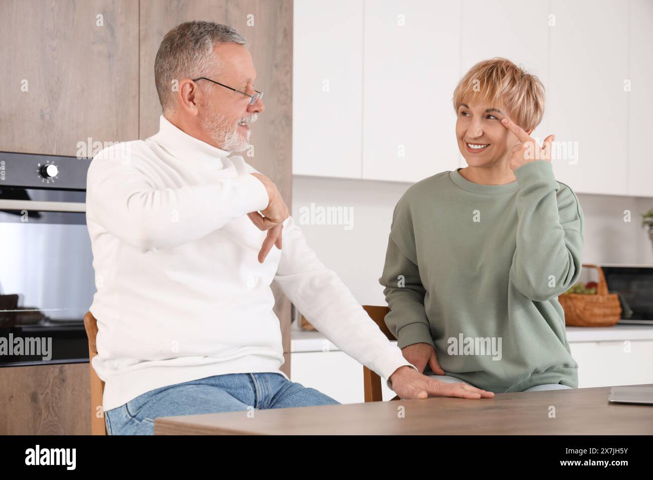 Mature deaf mute couple using sign language in kitchen Stock Photo - Alamy