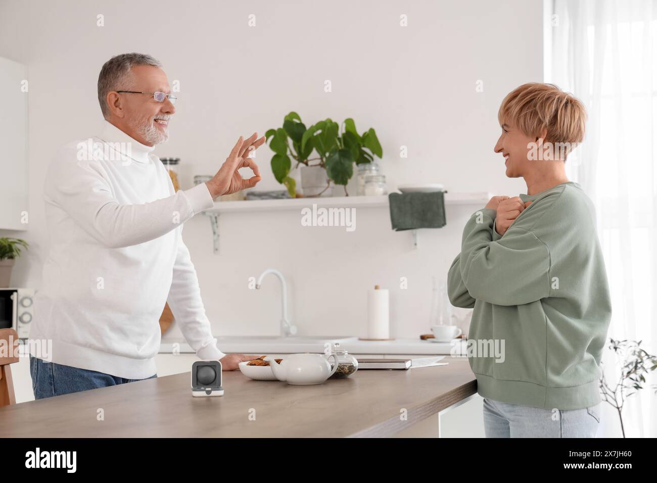 Mature deaf mute couple using sign language in kitchen Stock Photo - Alamy