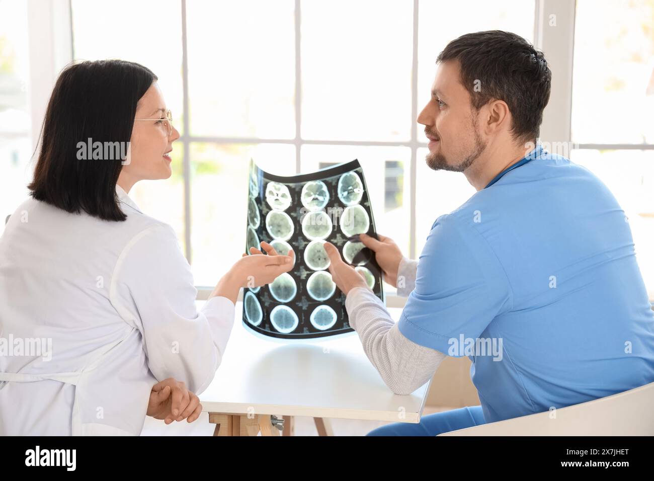 Doctors studying MRI scan at table in clinic, back view Stock Photo - Alamy