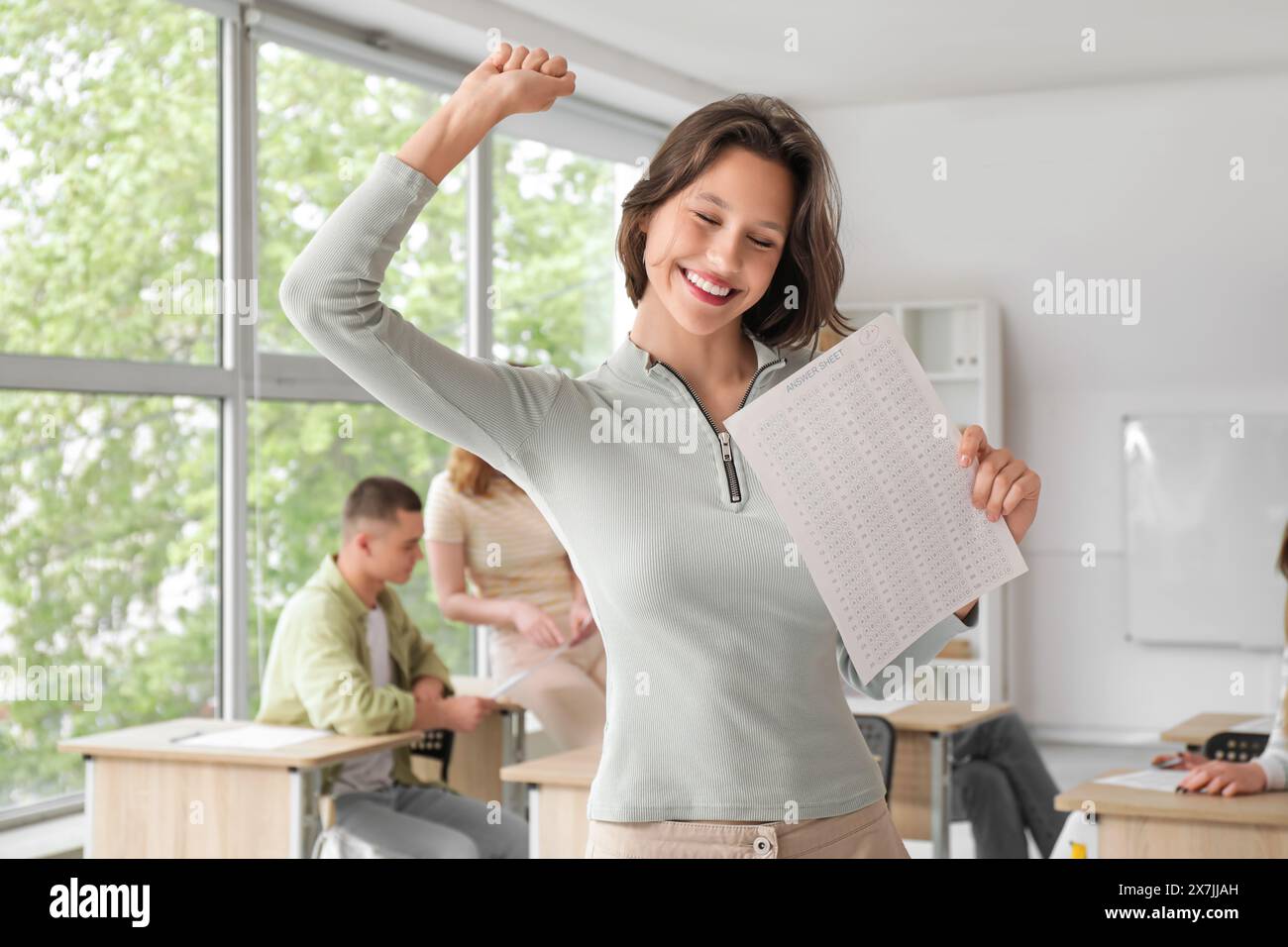 Happy female student with answer sheet after exam in classroom Stock ...
