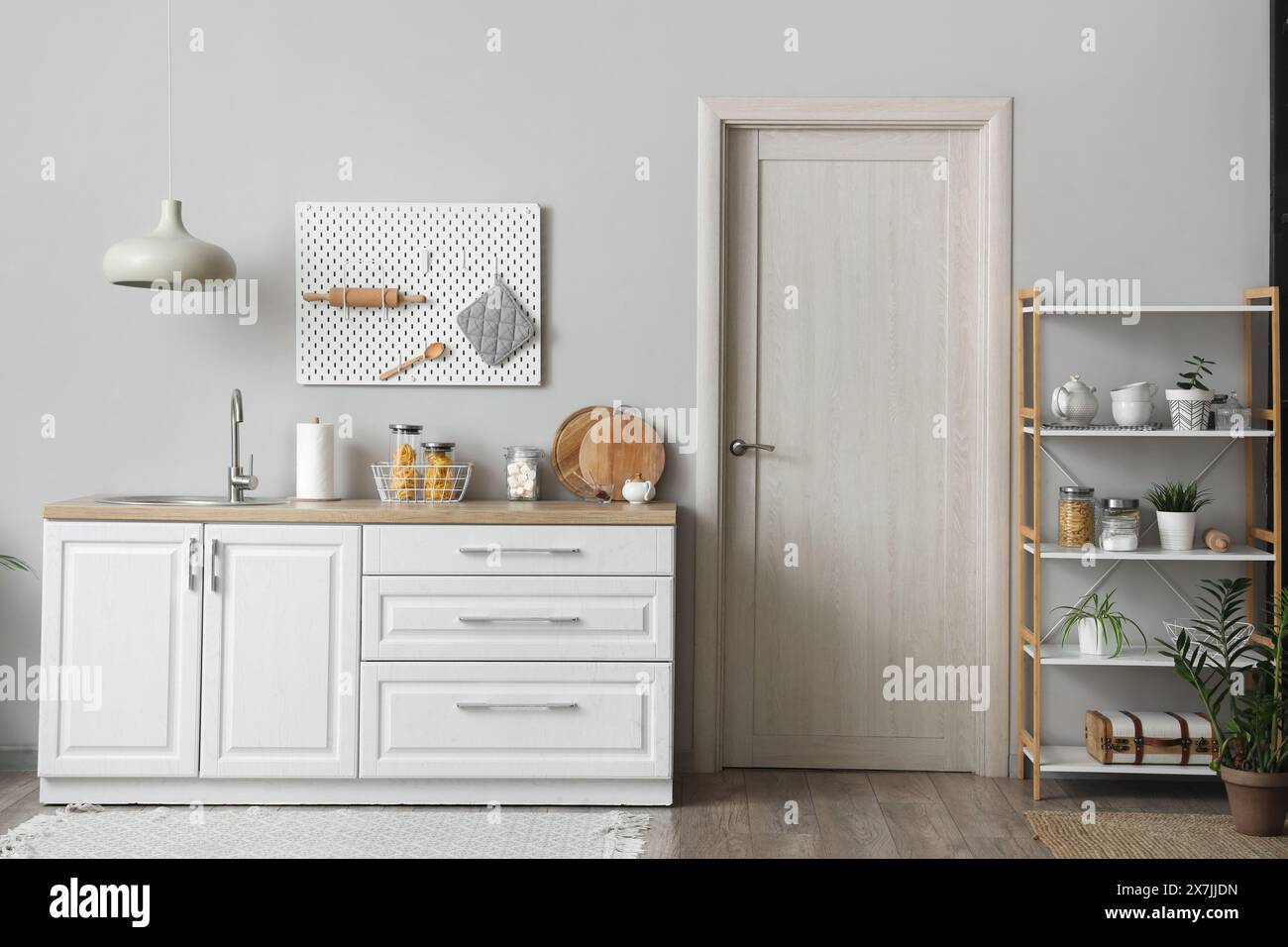 Interior of beautiful kitchen with white counters, door, shelving unit ...