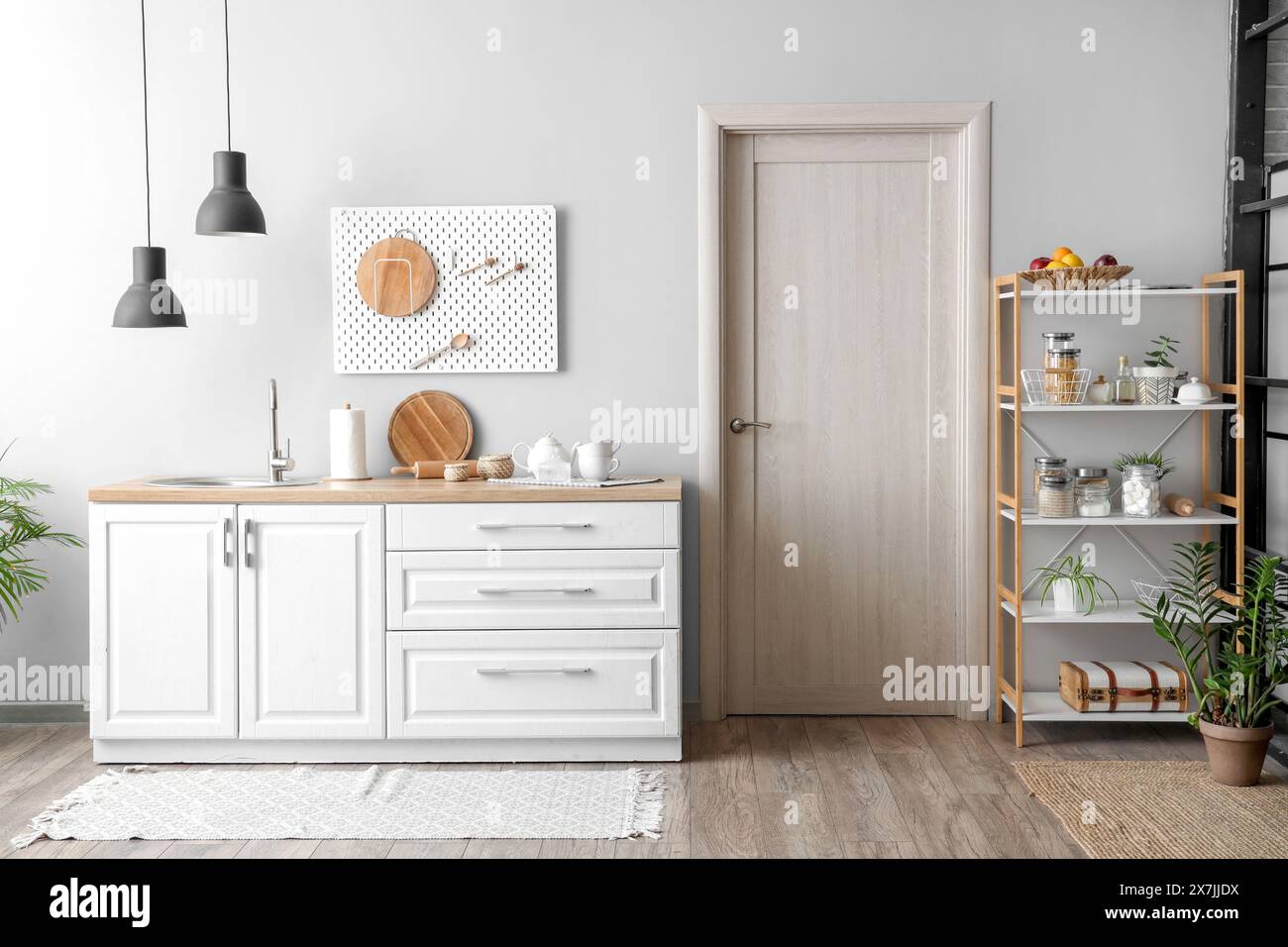 Interior of beautiful kitchen with white counters, door, shelving unit ...